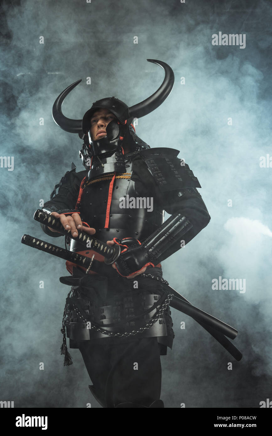 bottom view of samurai in japanese armor with swords on dark background ...