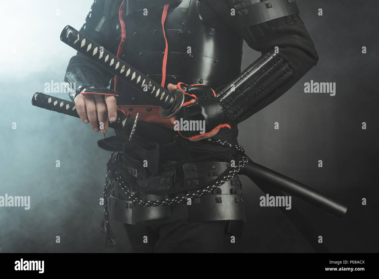 cropped shot of samurai in armor with swords on dark background with ...