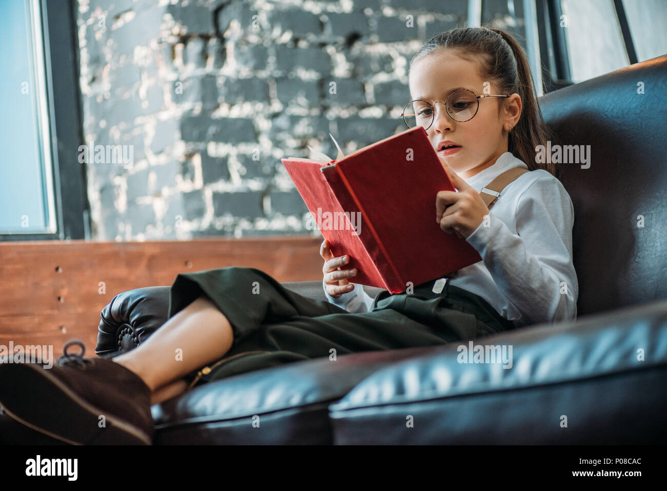 focused little child reading book on couch at home Stock Photo - Alamy