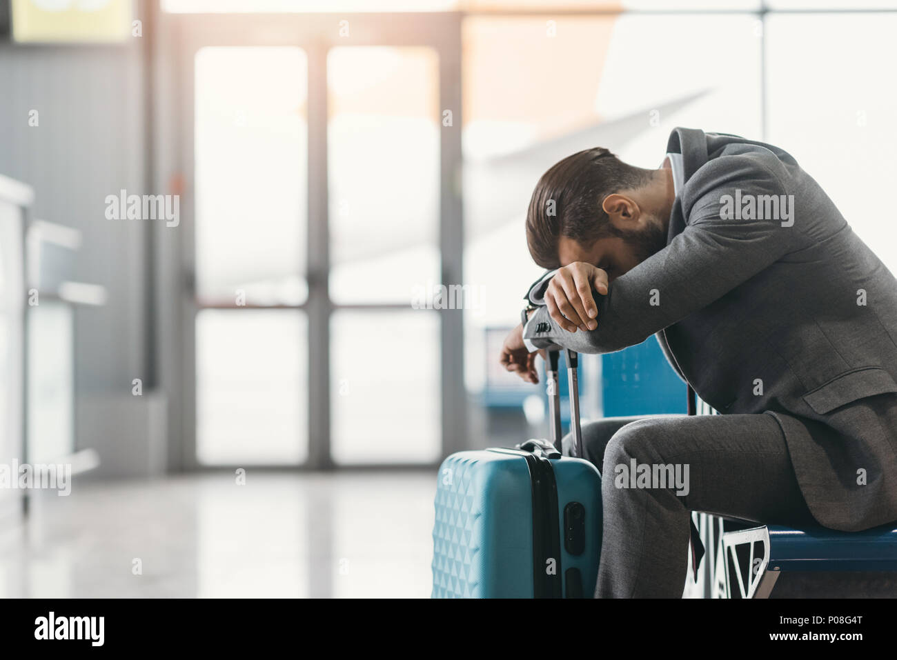 tired businessman sleeping at airport lobby while waiting for flight ...