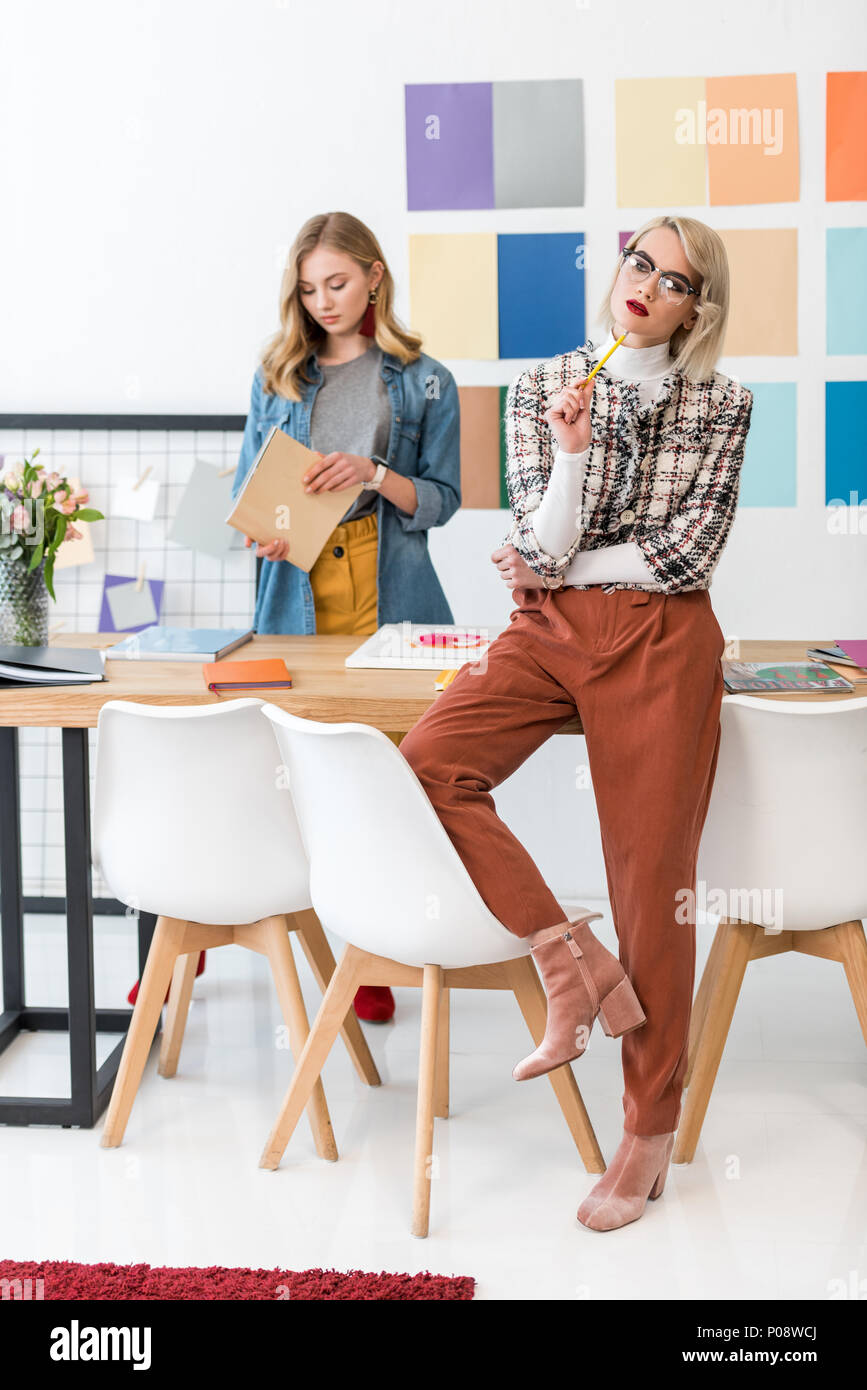 fashionable magazine editors doing paperwork at workspace with color ...
