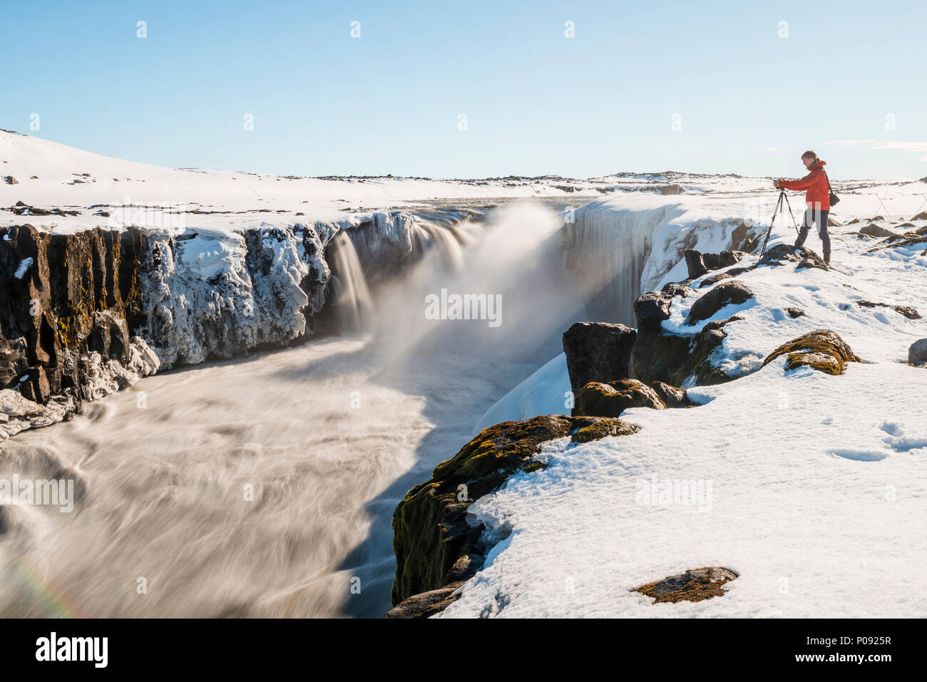 Photographing man at the edge of the Selfoss waterfall in winter, gorge ...