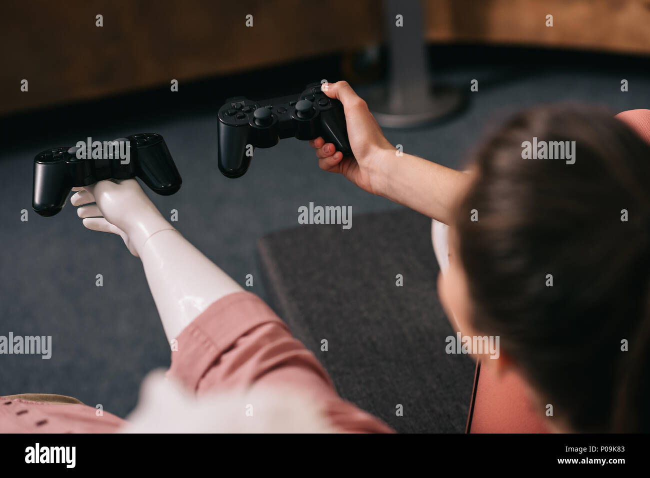 partial view of woman with manikin near by playing video game at home ...