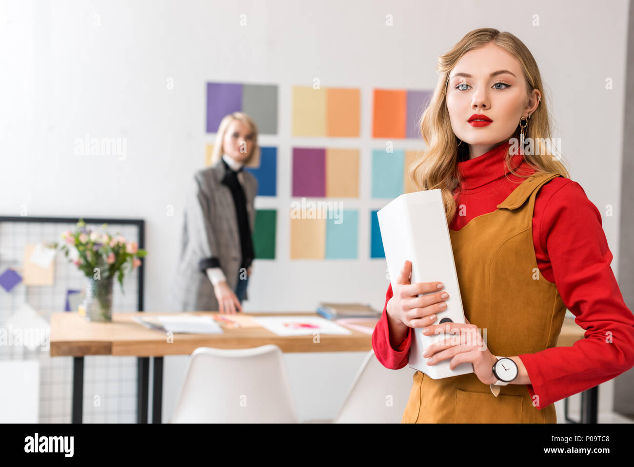 fashion magazine editor with folder in modern office with colleague and ...
