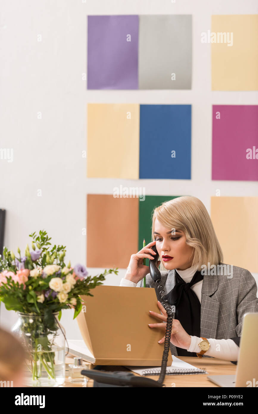 attractive fashion magazine editor working with documents and talking ...