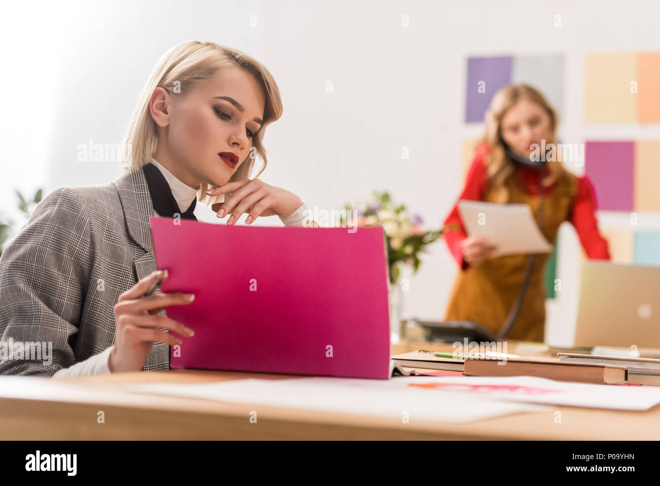 fashion magazine editor doing paperwork in modern office with colleague ...