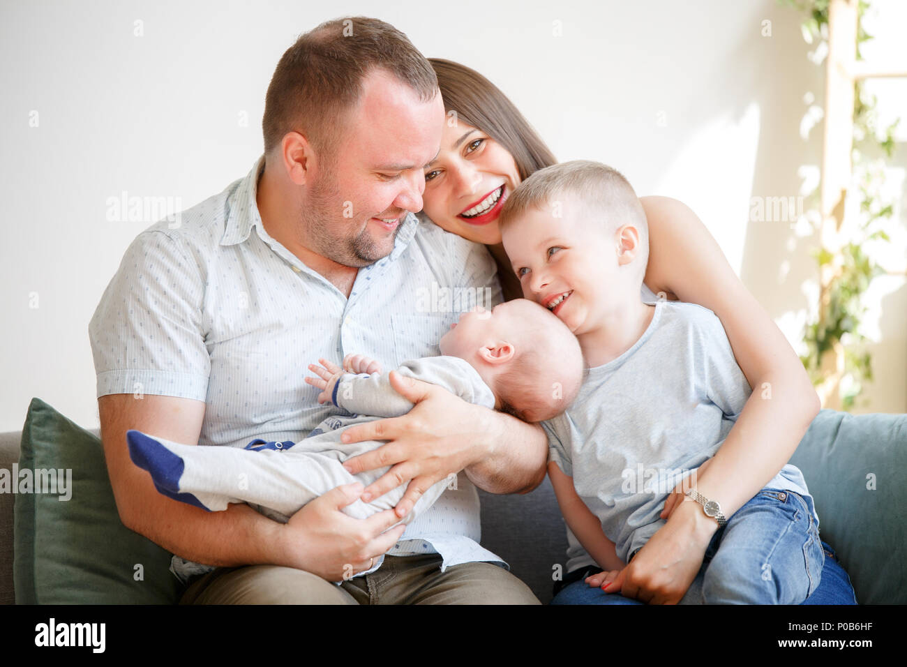 Portrait of happy parents with two sons on sofa Stock Photo - Alamy