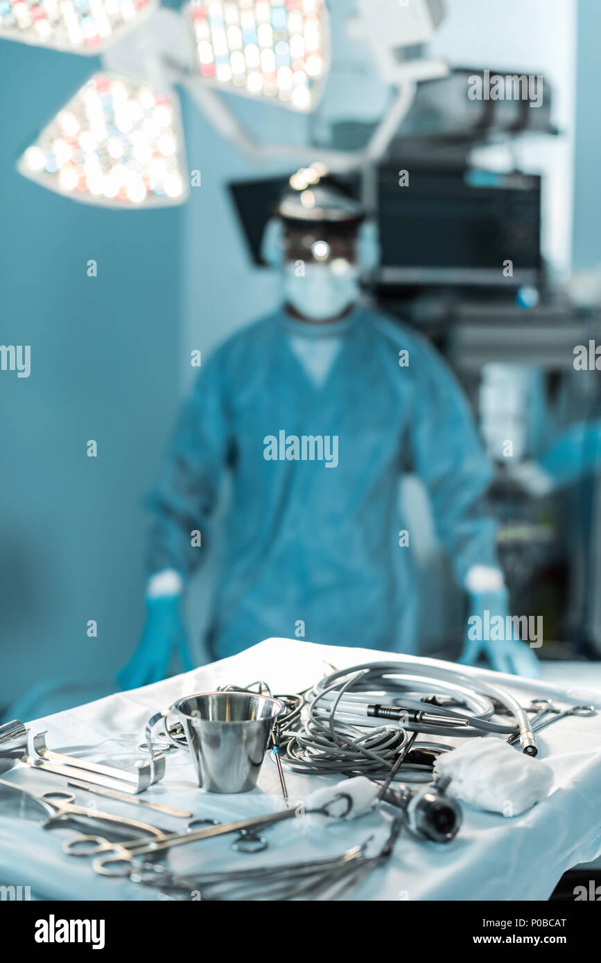surgeon looking at camera in operating room with tools on foreground ...