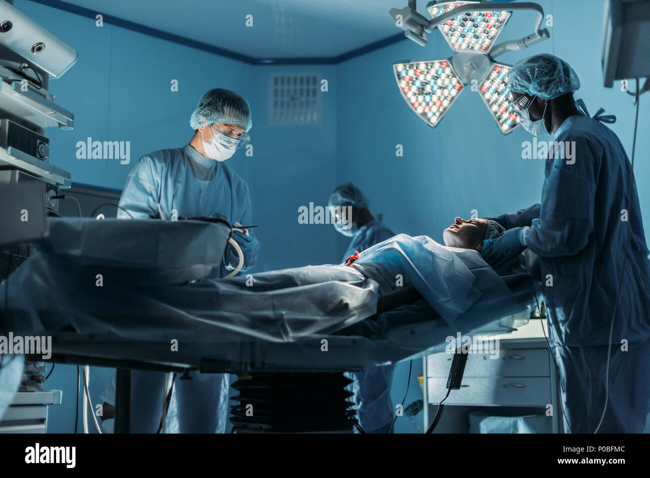 multicultural doctors preparing patient for surgery in operating room ...