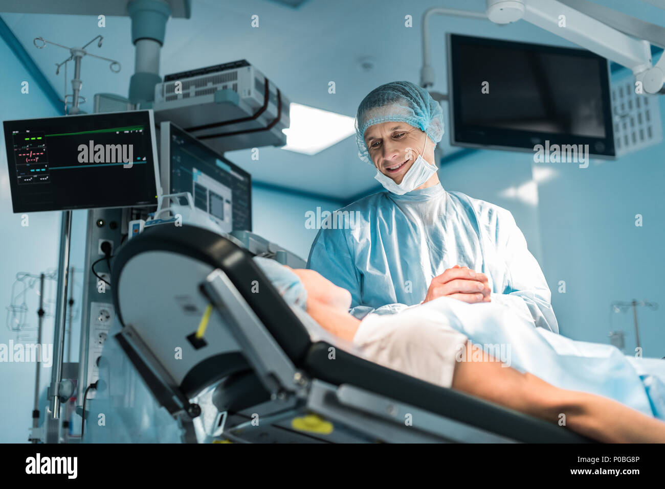 bottom view of smiling doctor and patient holding hands in operating ...