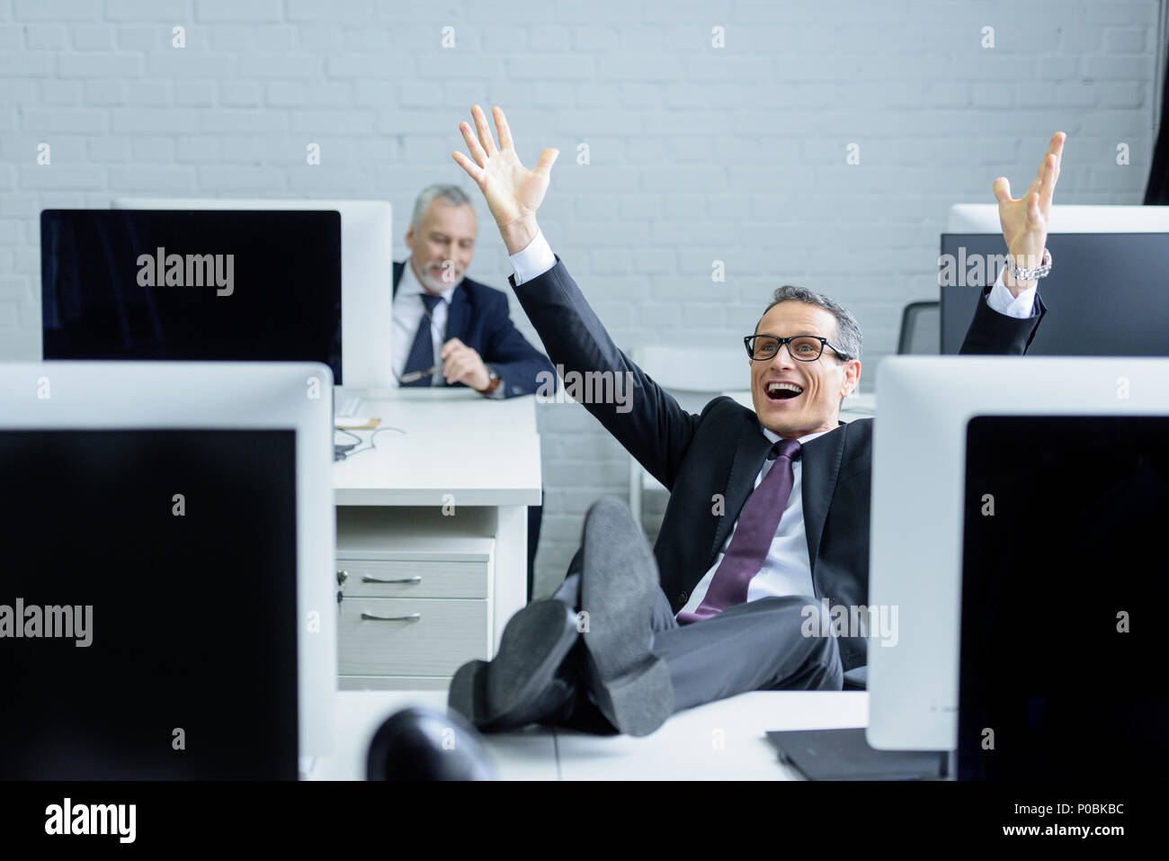 selective focus of happy businessman sitting at workplace with legs on ...