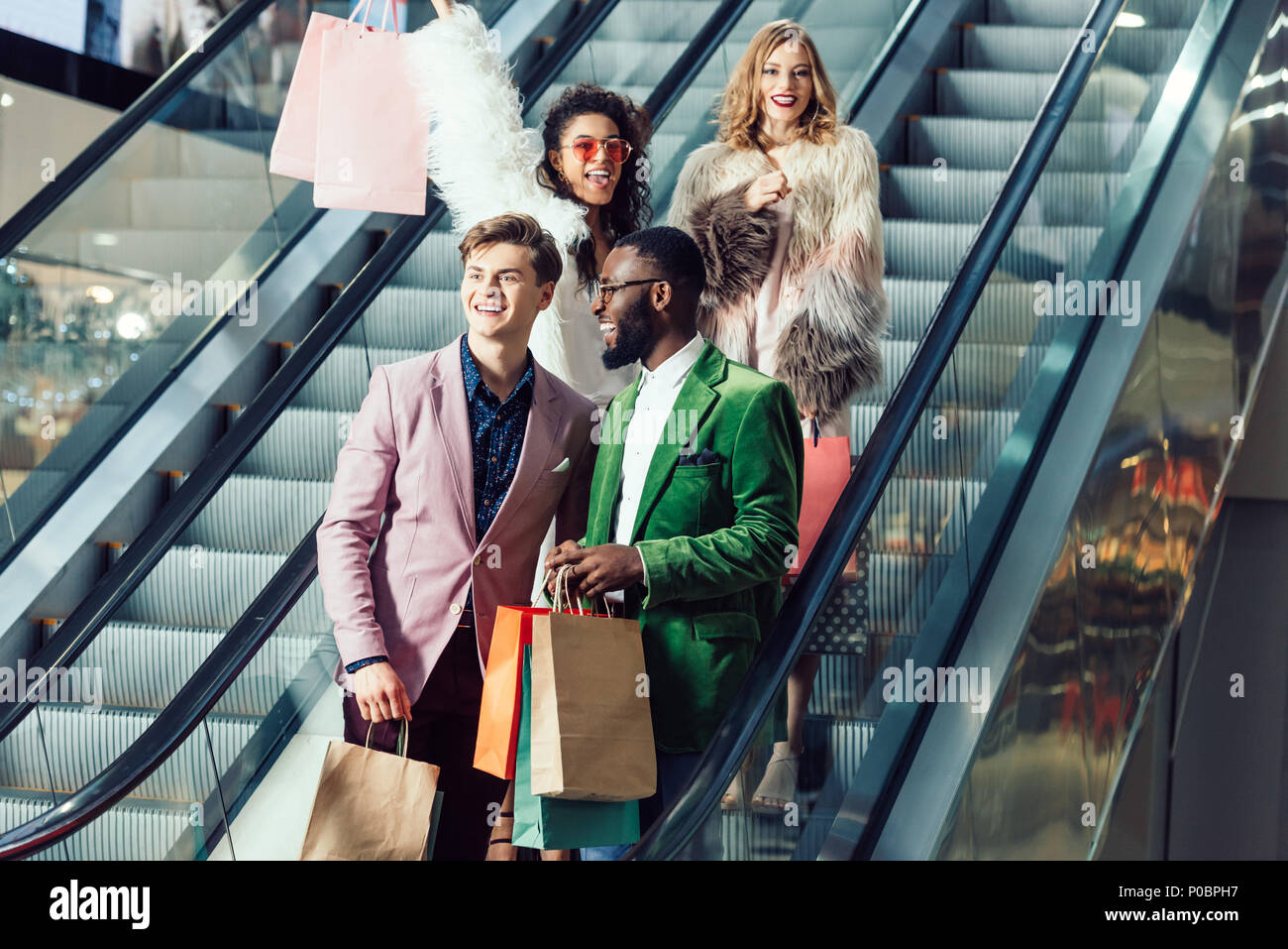 group of multiethnic shoppers on escalator at mall with packages Stock ...