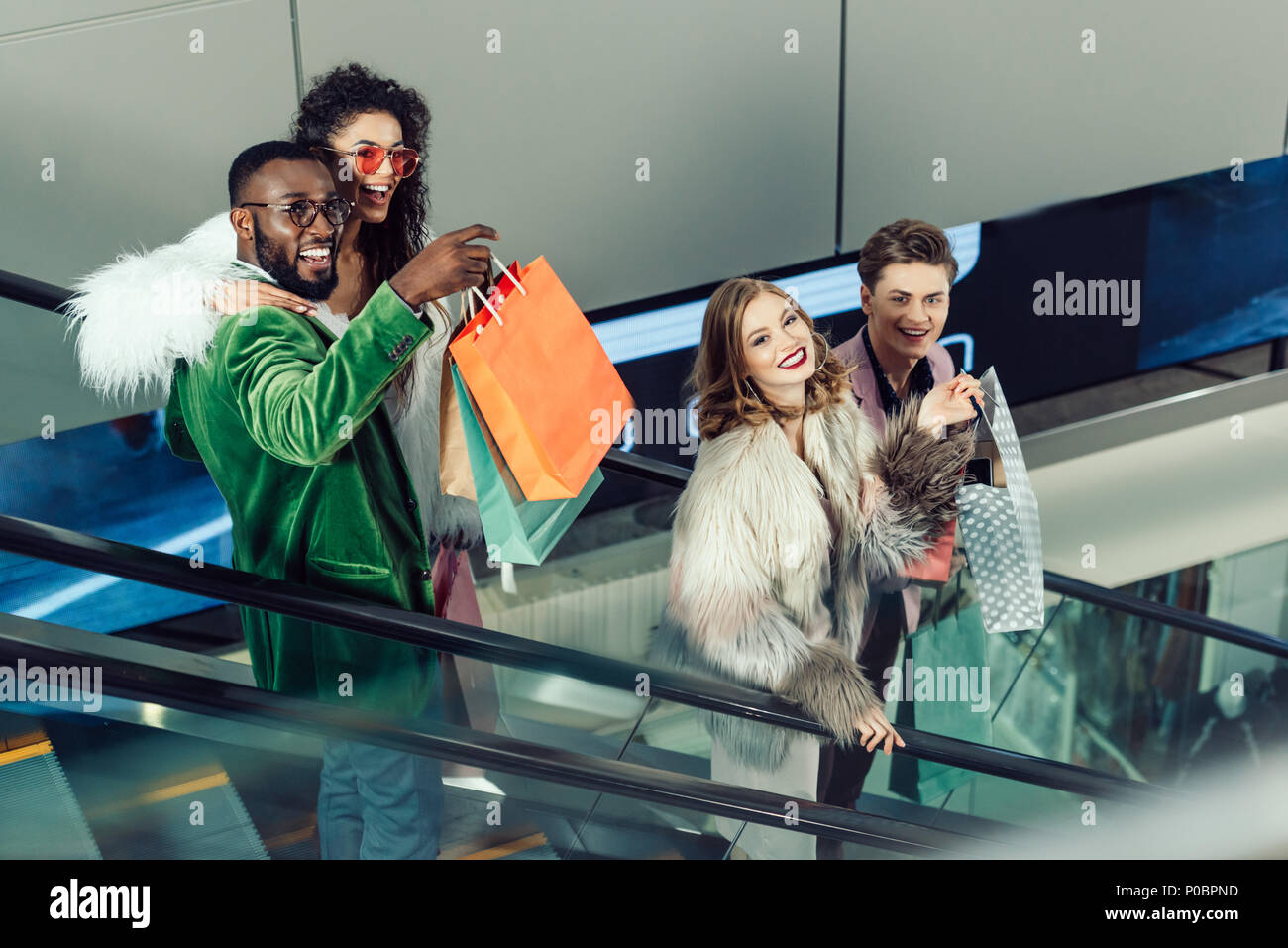 young stylish group of shoppers on escalator at shopping mall Stock ...