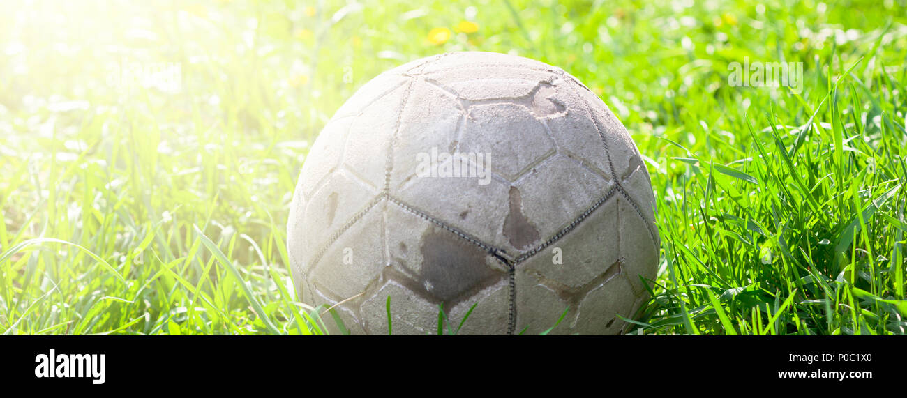 Old soccer ball forgotten in the green grass field. The football ...