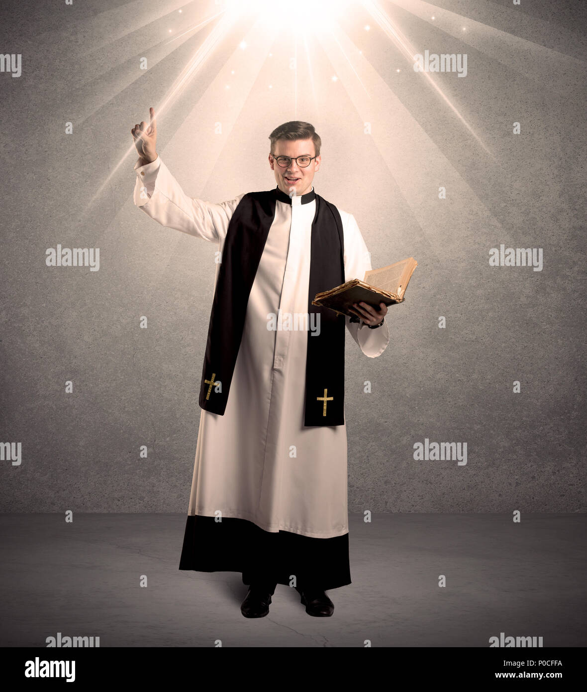A male religious young priest in black and white dress giving his ...