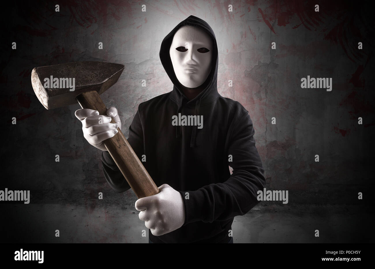 Armed rude assassin in an empty bloody room concept with gun ax ...