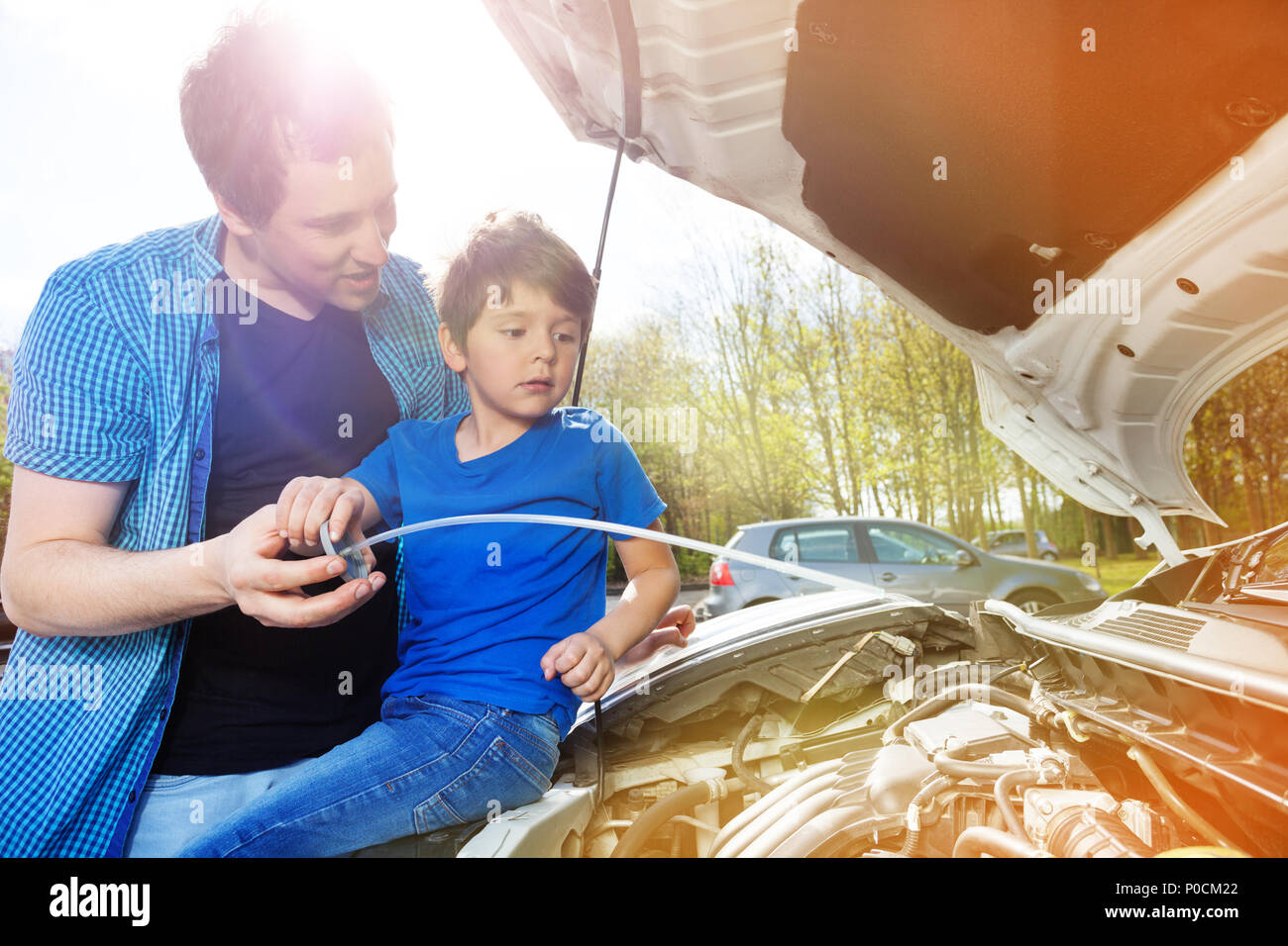 Father showing his 6 years old kid the oil level in car engine near the ...