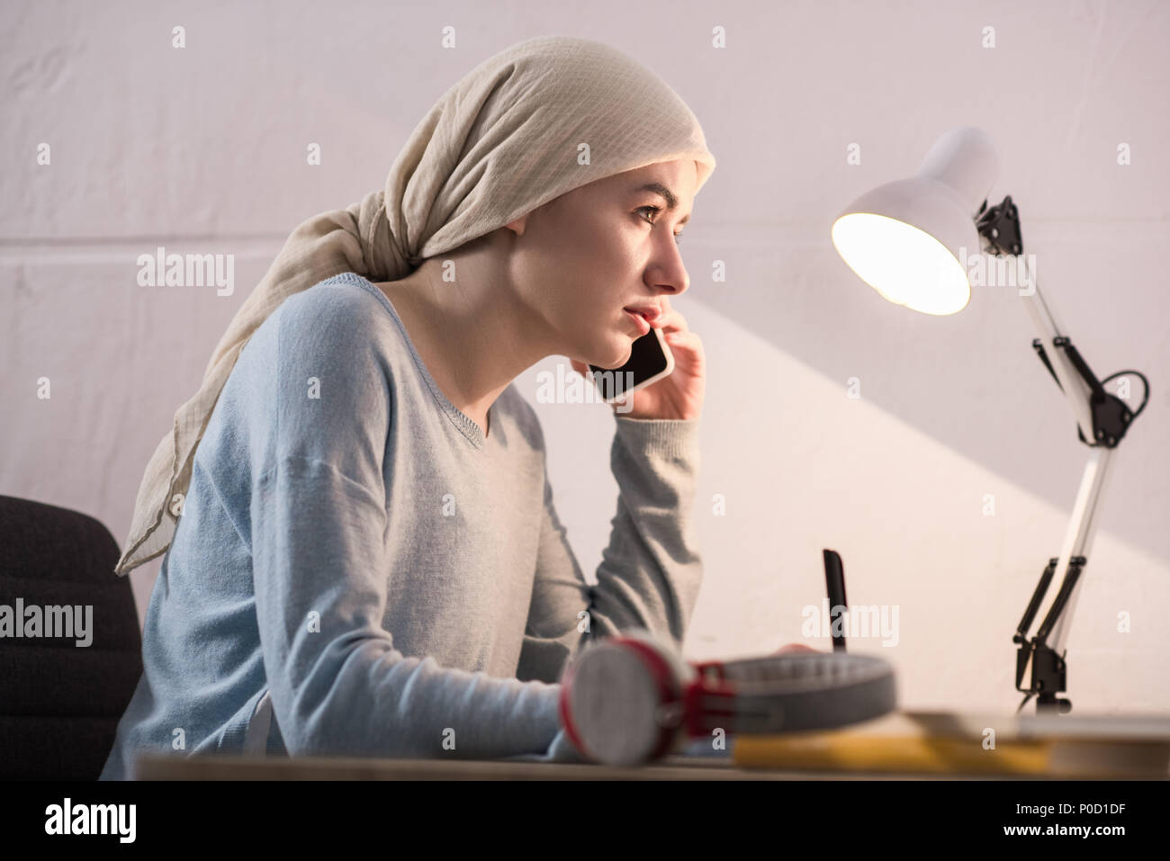 side view of young woman in kerchief talking by smartphone and taking ...