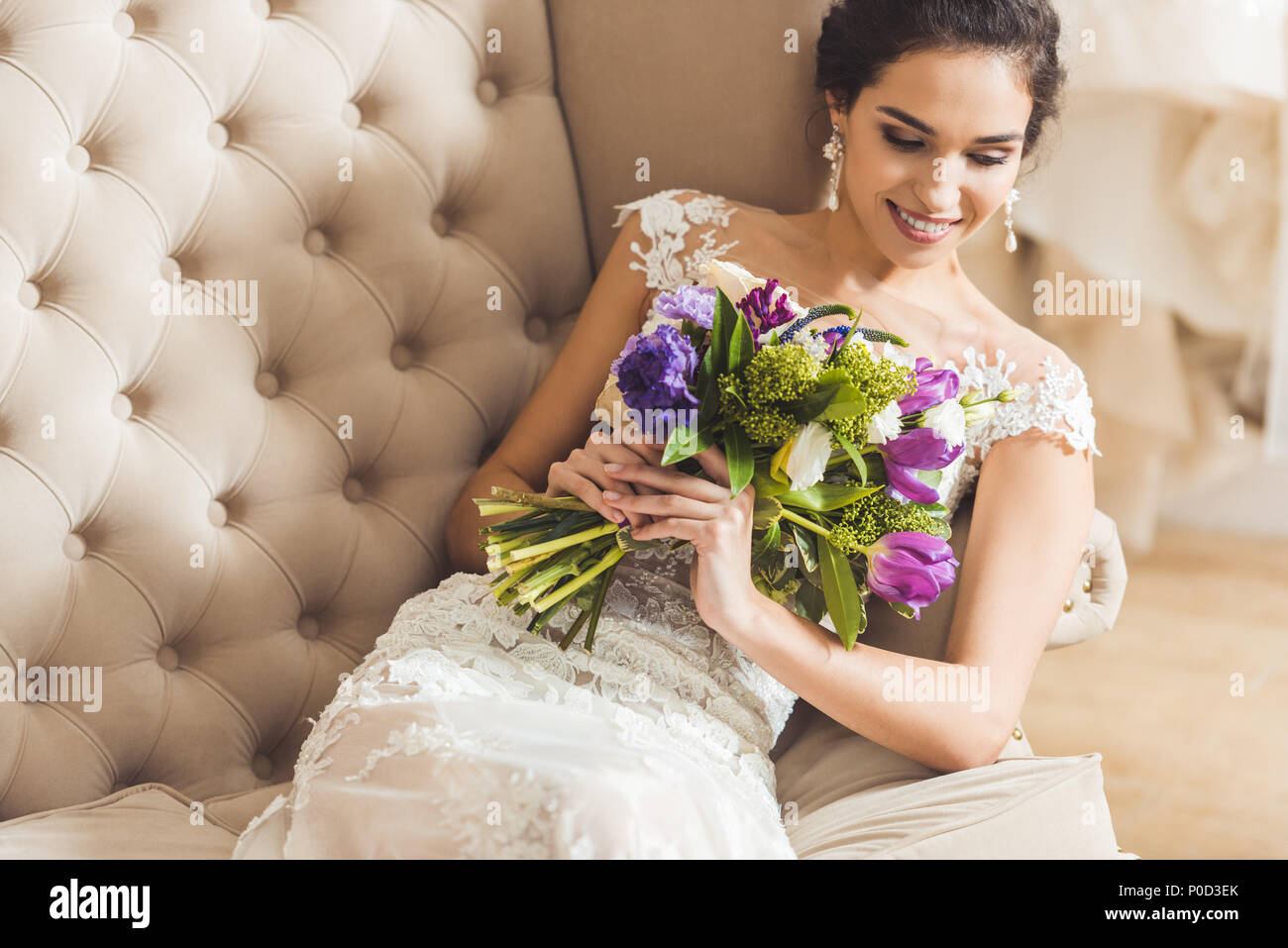 Beautiful bride with floral bouquet on sofa in wedding salon Stock ...