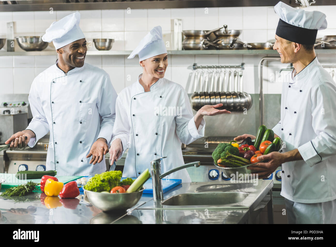 smiling multicultural chefs talking at restaurant kitchen Stock Photo ...