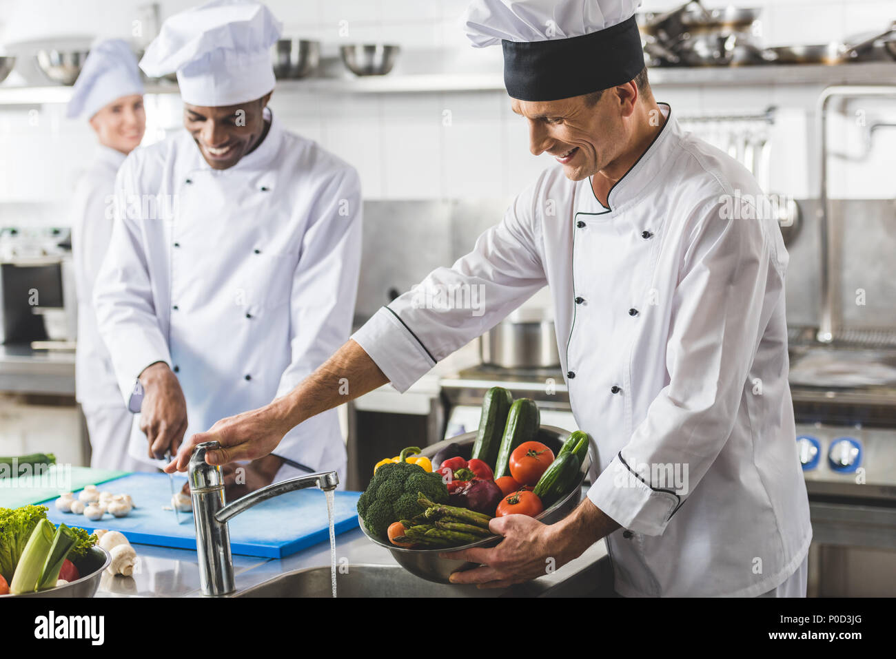 multicultural chefs cutting and washing vegetables at restaurant ...