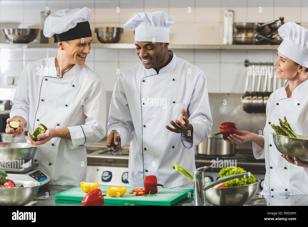 smiling multicultural chefs talking at restaurant kitchen Stock Photo ...
