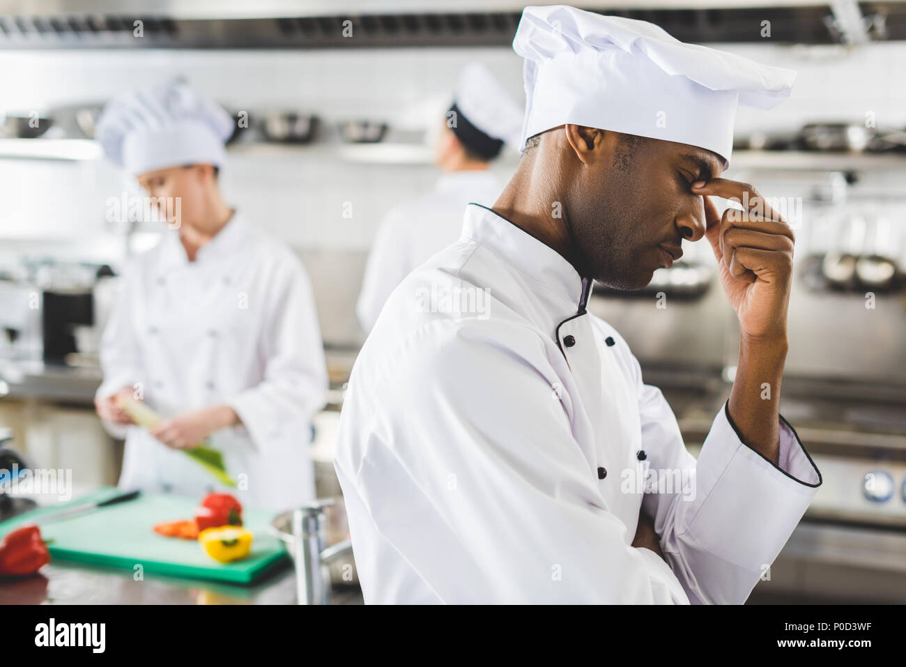 tired african american chef touching nose bridge at restaurant kitchen ...