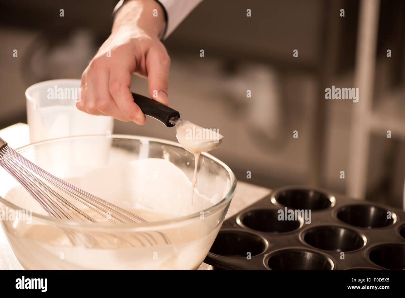partial view of confectioner pouring dough into baking forms Stock ...