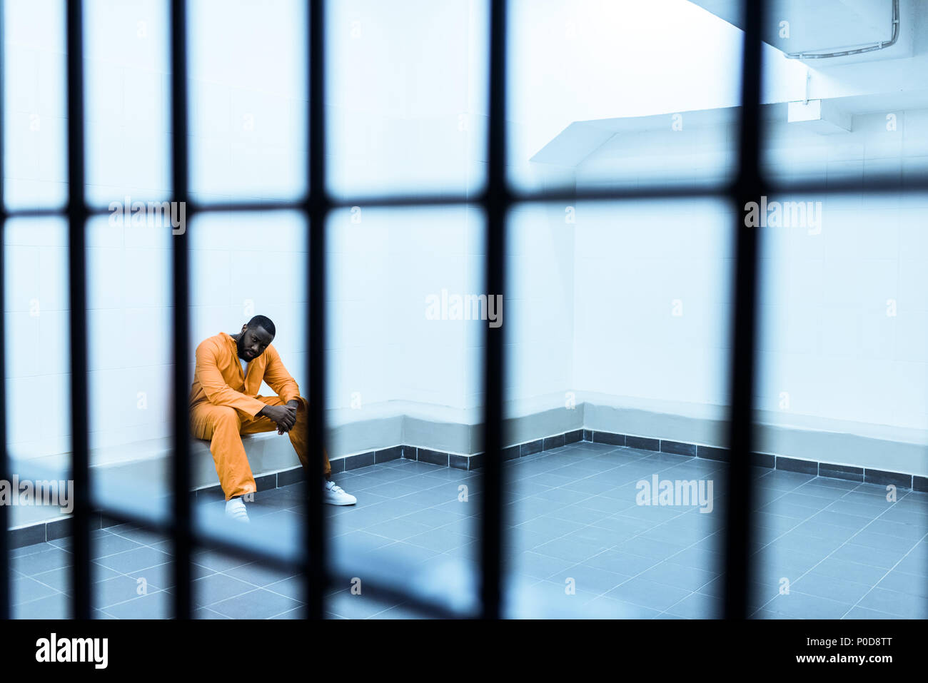 african american prisoner sitting on bench behind prison bars Stock ...