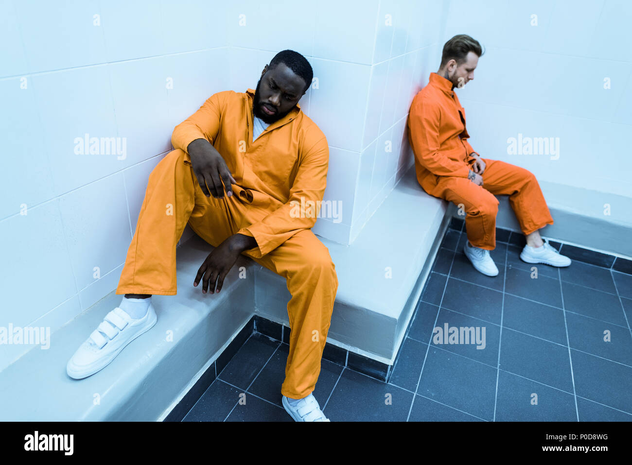 high angle view of multicultural prisoners sitting on benches in prison ...
