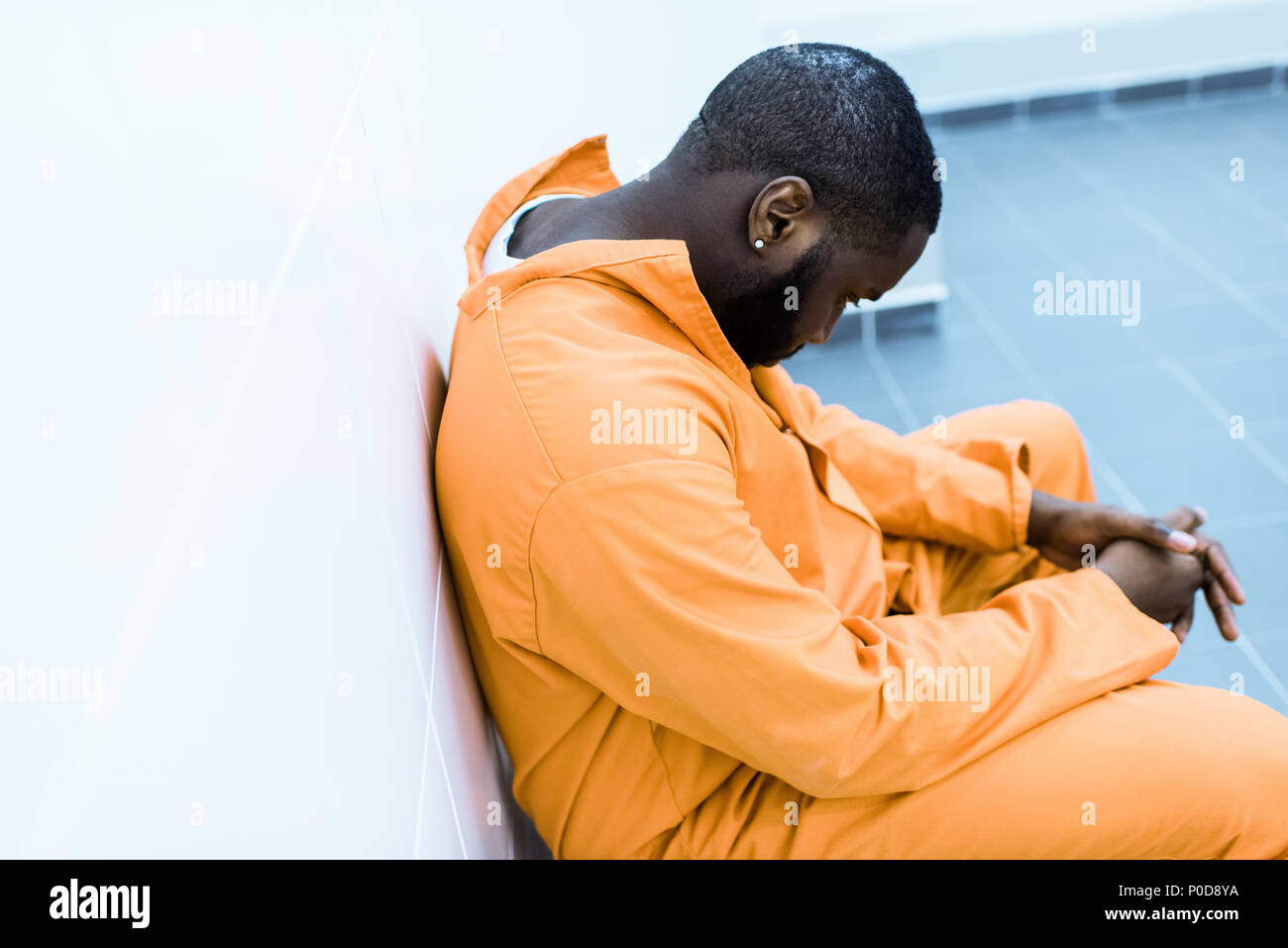 sad african american prisoner sitting on bench in prison cell Stock ...
