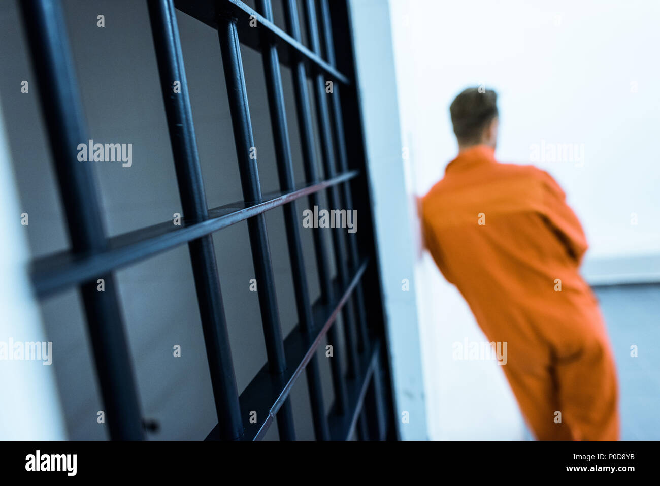rear view of prisoner leaning on wall in prison cell Stock Photo - Alamy