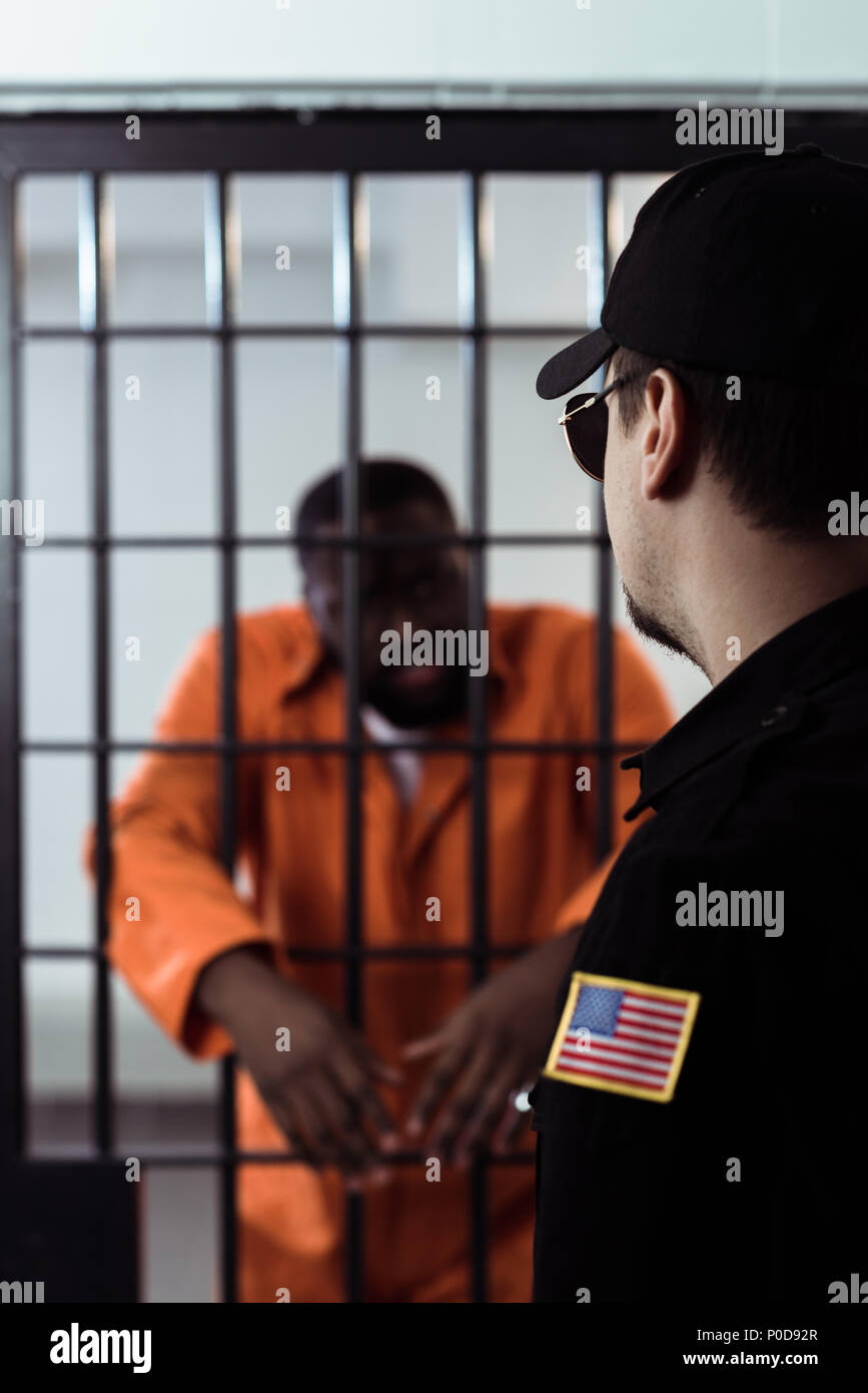 security guard standing near prison bars and looking at african ...