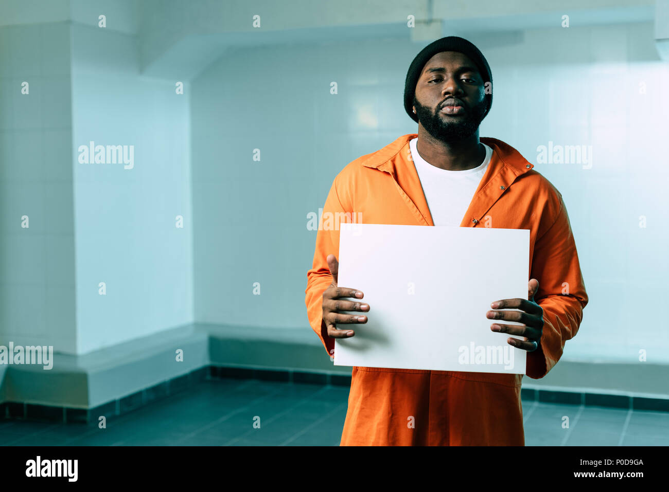 african american prisoner holding blank placard and looking at camera ...