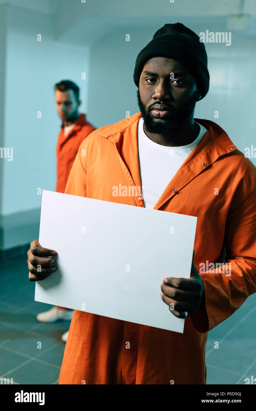 african american prisoner holding blank placard and looking at camera ...