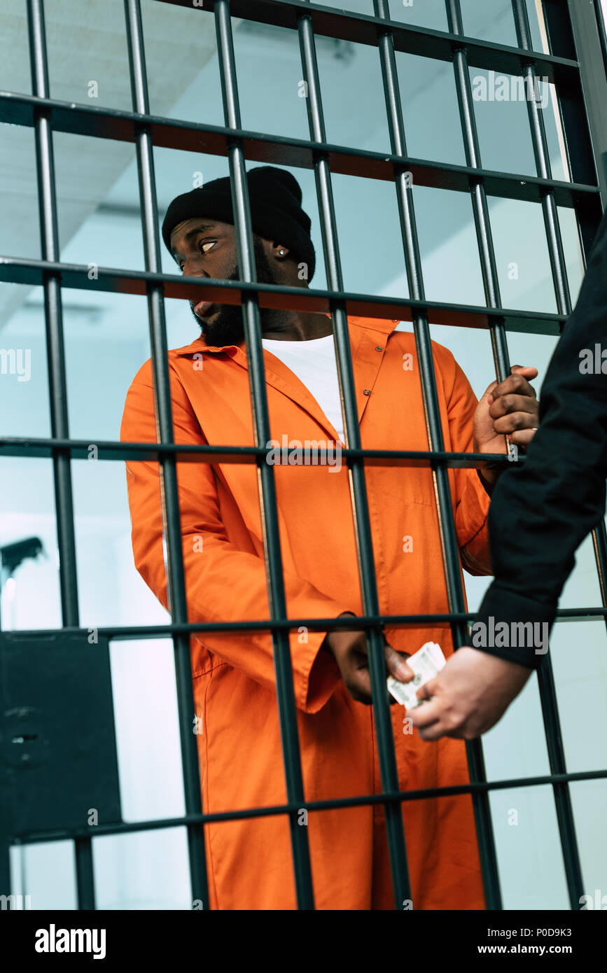 cropped image of african american prisoner giving money to security ...