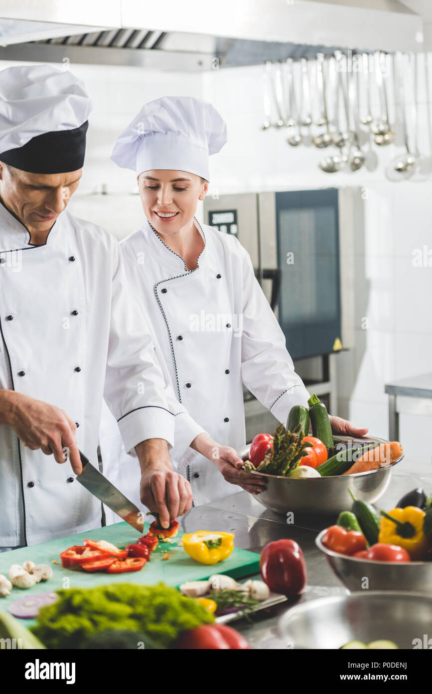 Male chef watching female colleague prepare food in the kitchen Stock ...