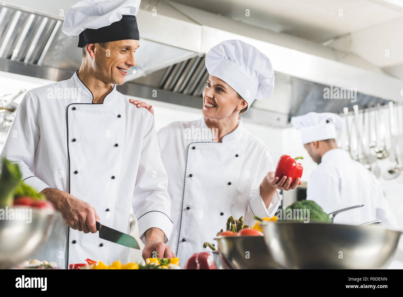 chef showing bell pepper and palming colleague while he cutting ...