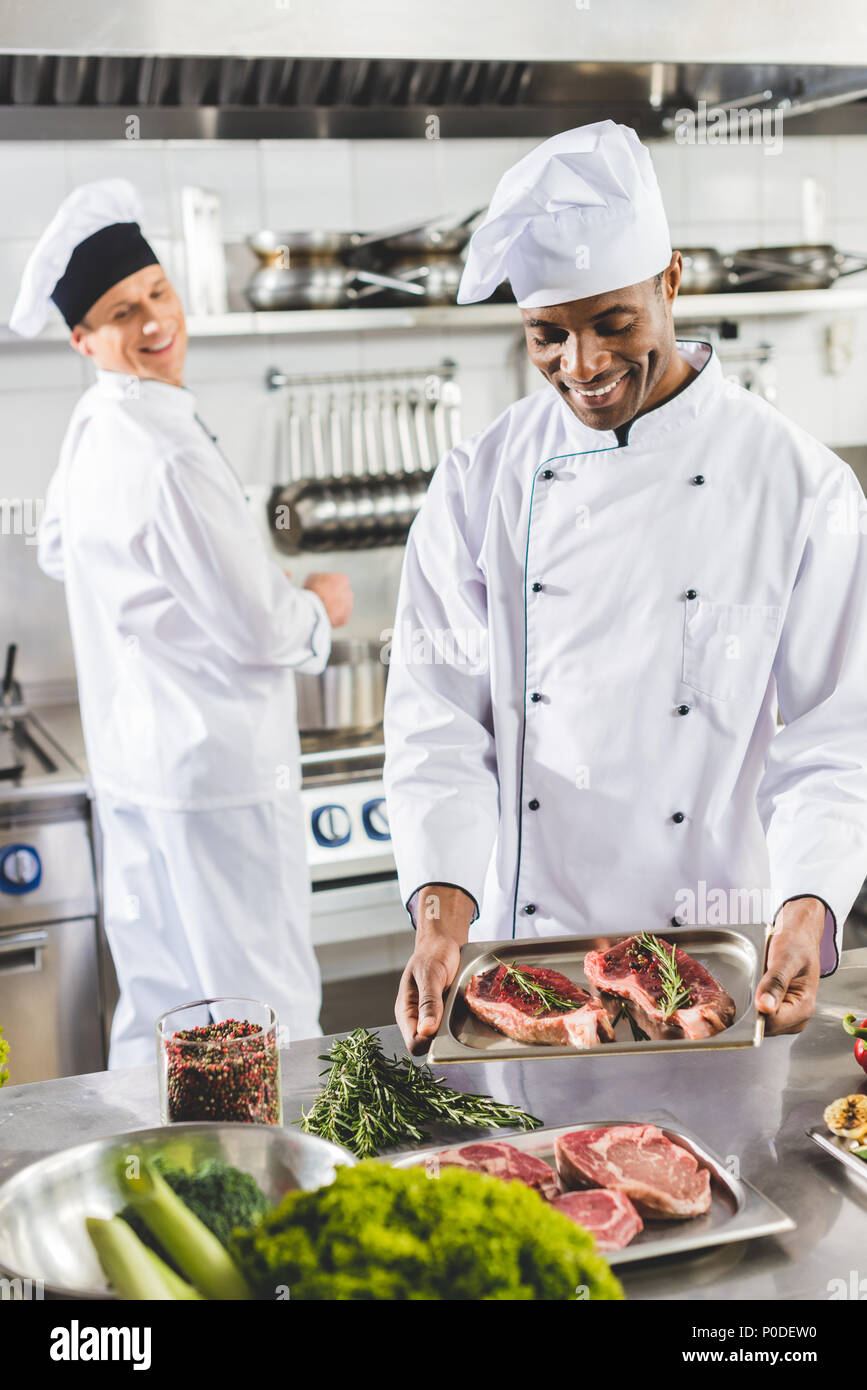 happy multicultural chefs cooking steaks at restaurant kitchen Stock ...