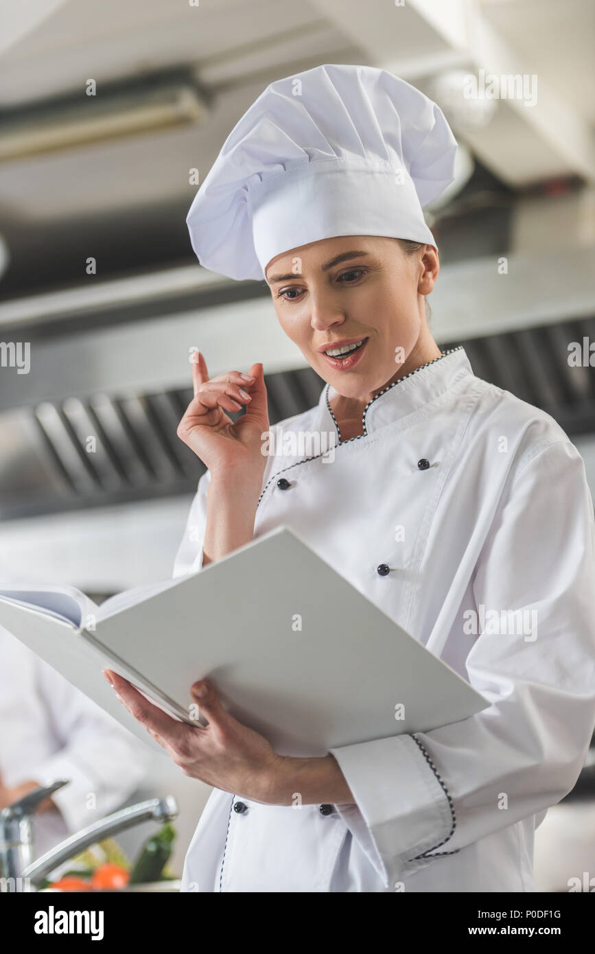 attractive chef reading recipe and showing idea gesture at restaurant ...