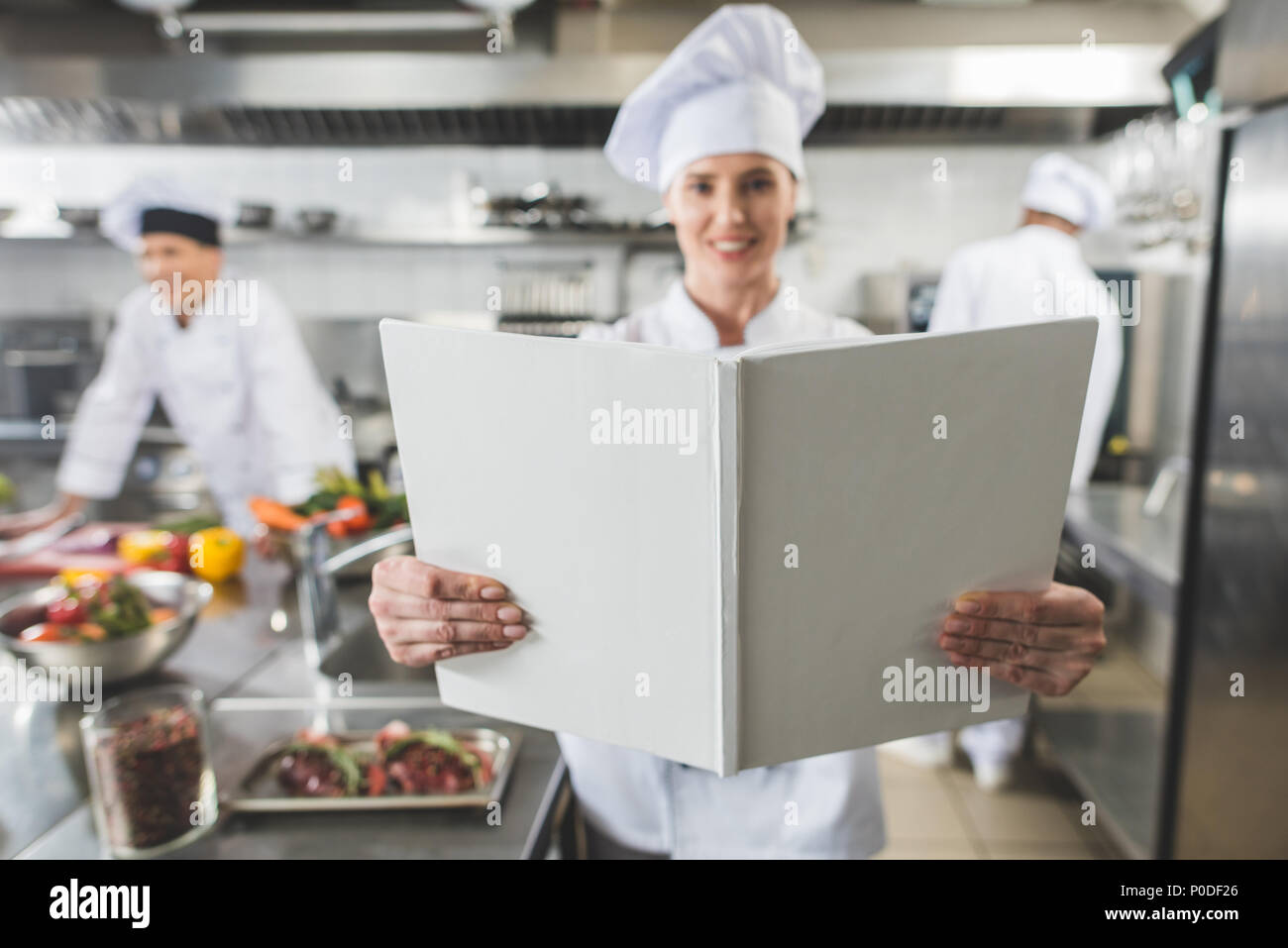 smiling chef holding recipe book at restaurant kitchen Stock Photo - Alamy