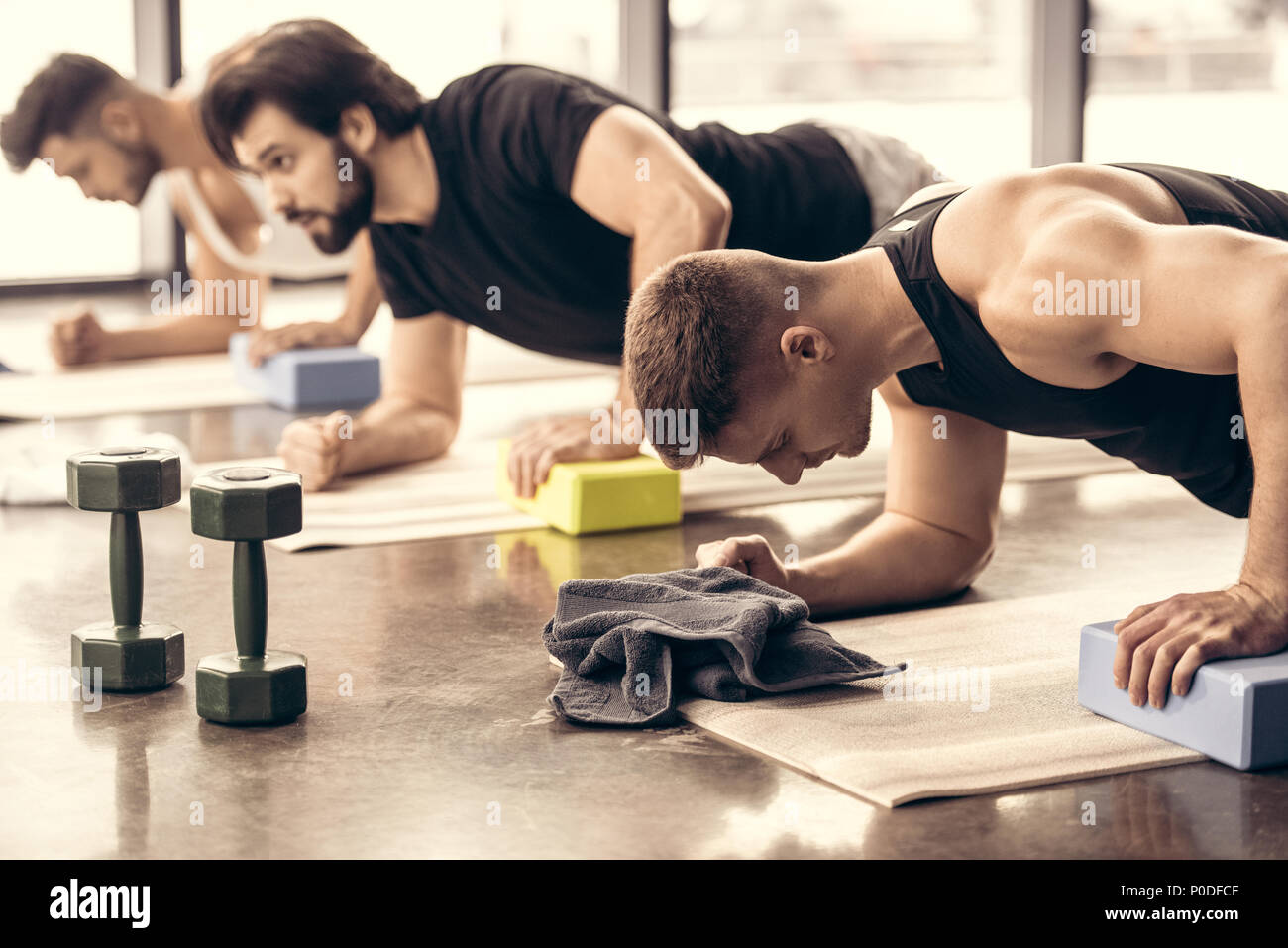 handsome sportsmen simultaneously doing plank and using blocks in gym ...