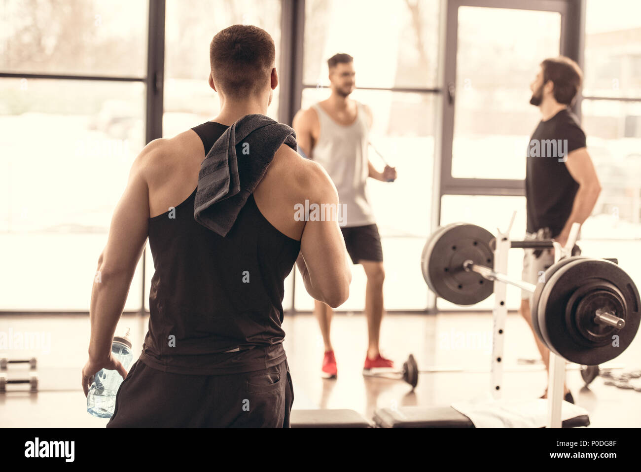 back view of muscular sportsman looking at friends in gym Stock Photo ...