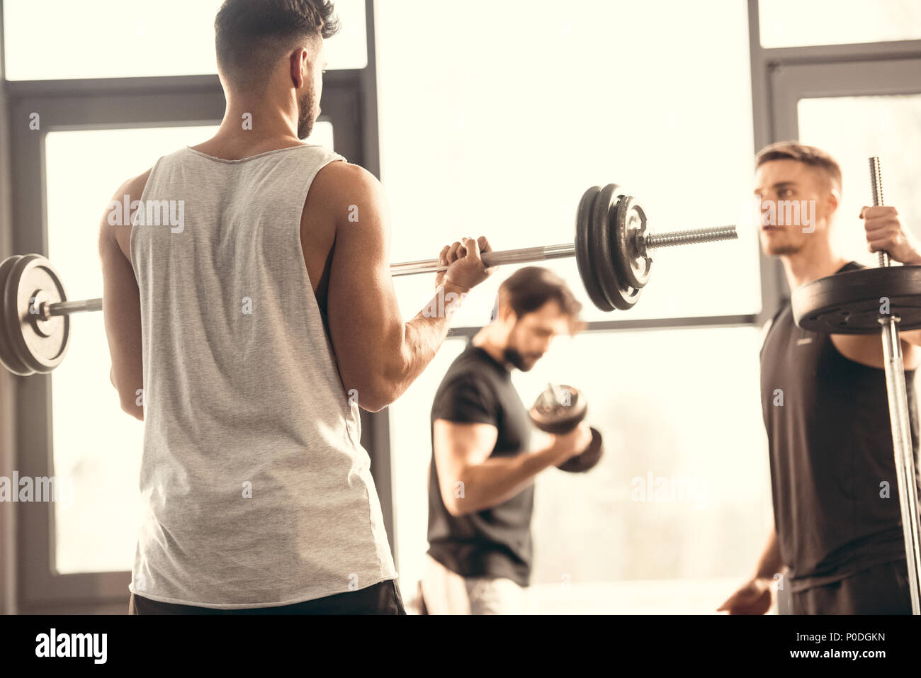 young sportsmen training with barbells in sports center Stock Photo - Alamy