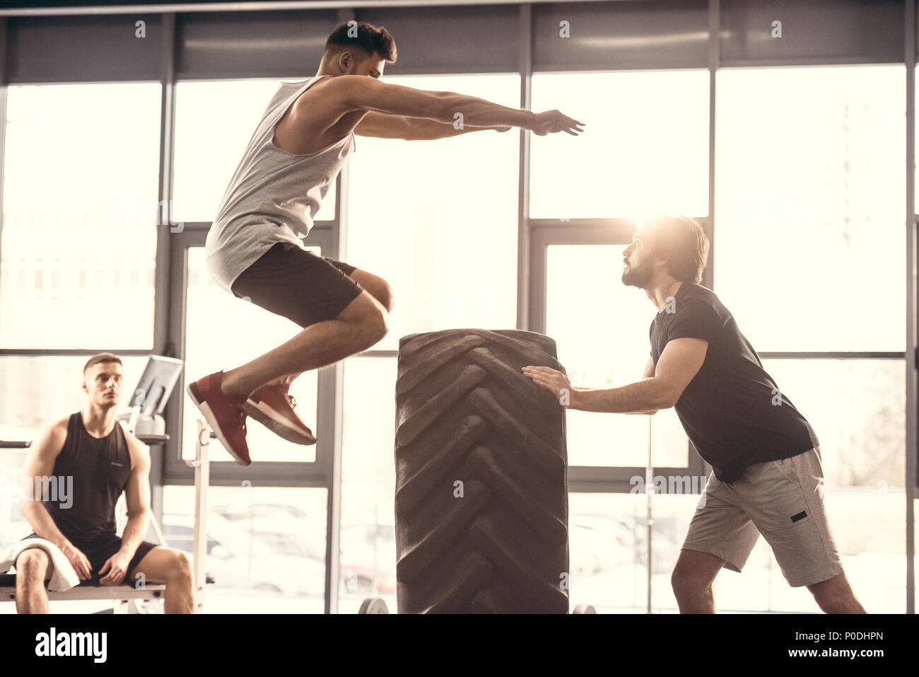 side view of athletic young men training with tire in gym Stock Photo ...