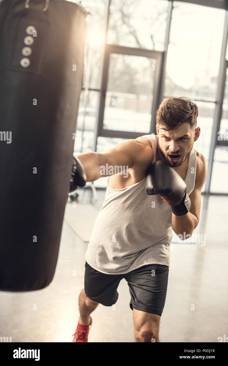emotional young sportsman training with punching bag in gym Stock Photo ...