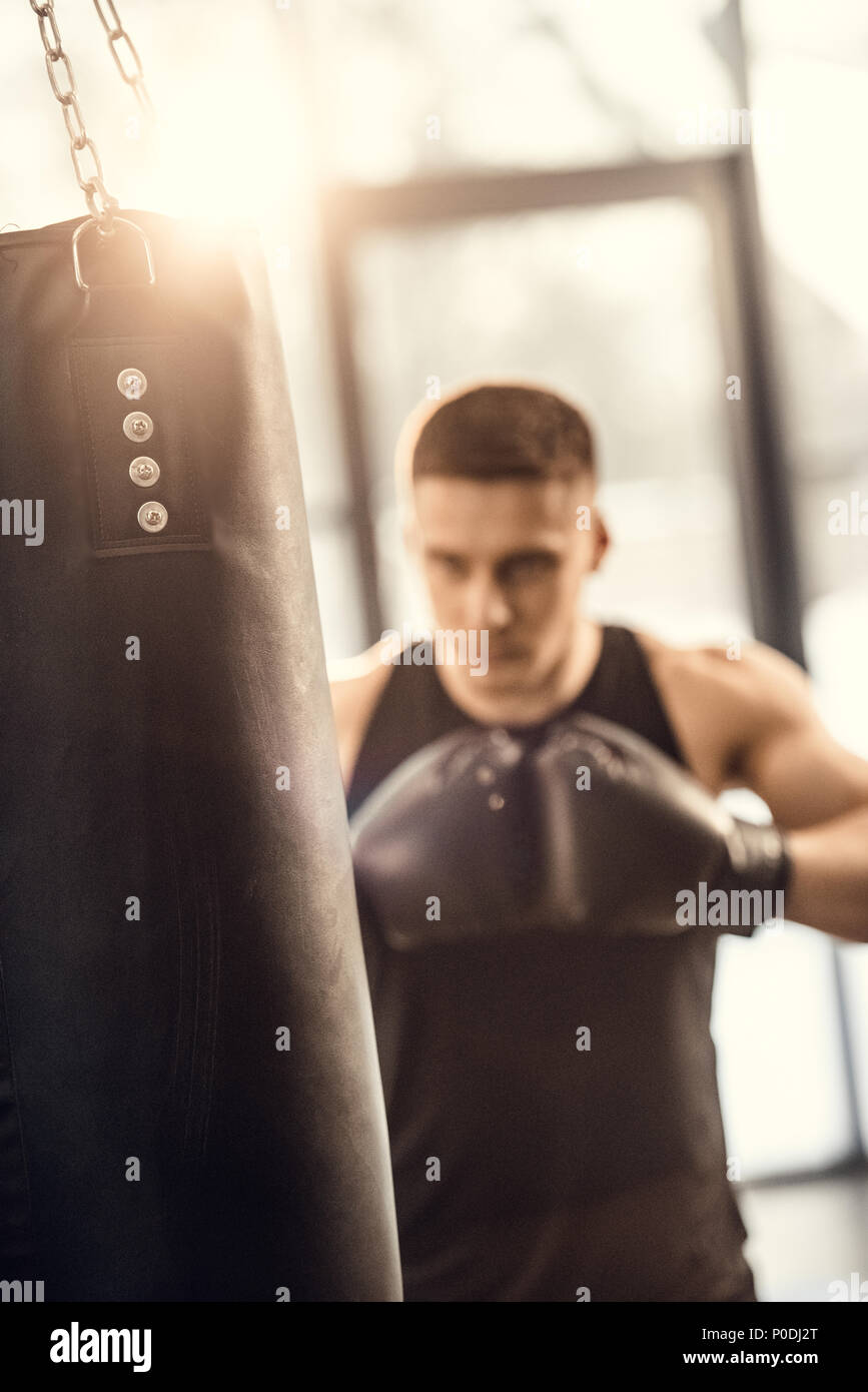 selective focus of athletic young man boxing with punching bag Stock ...
