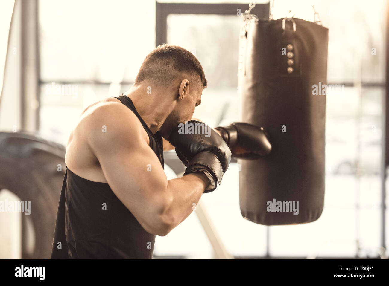 side view of muscular young boxer training with punching bag Stock ...
