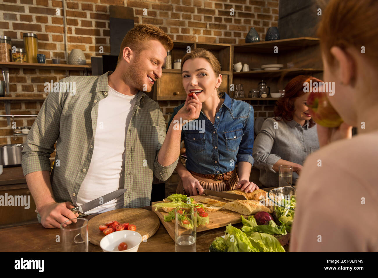 husband feeding wife while cooking dinner together at home Stock Photo ...