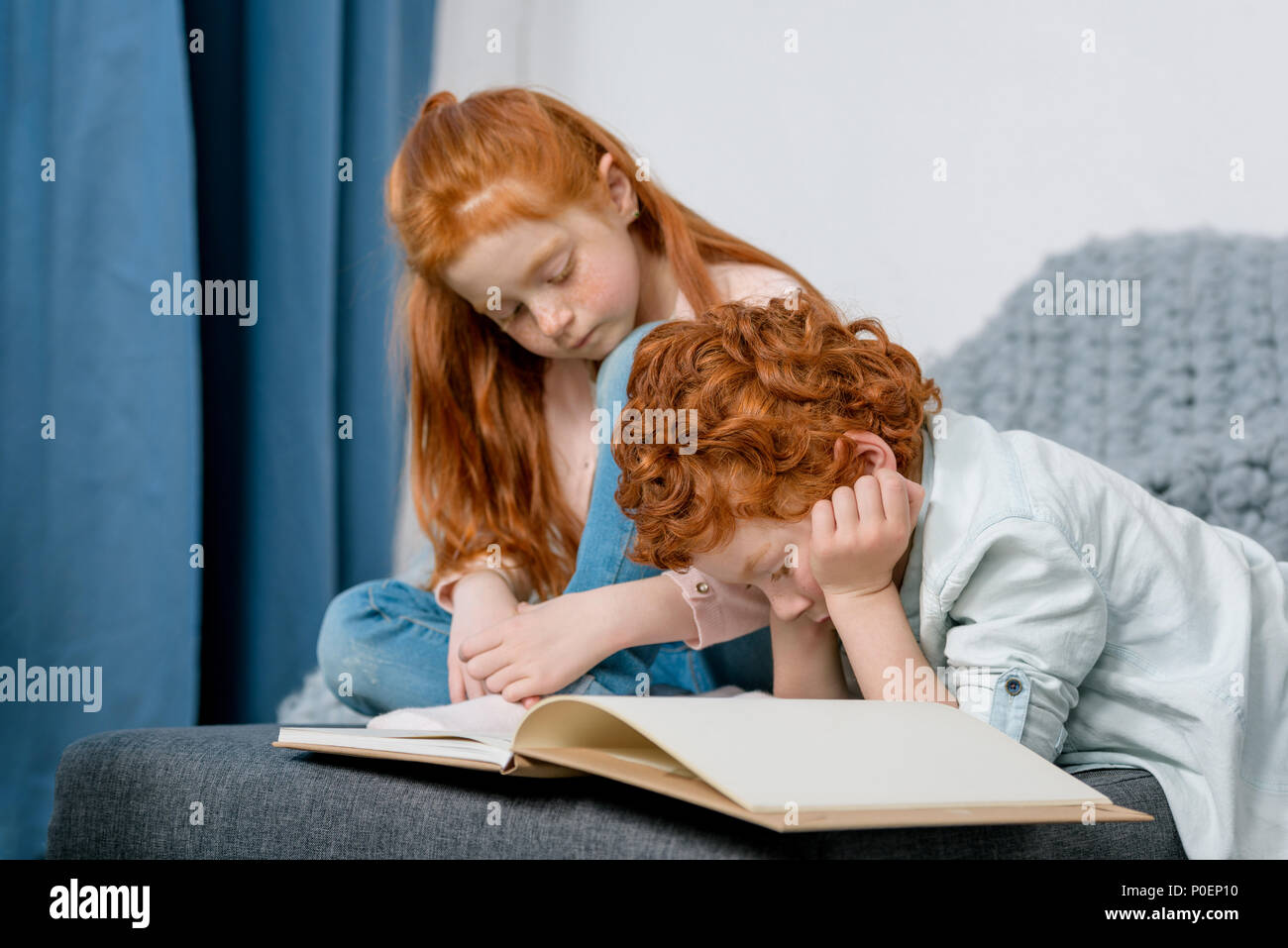 little concentrated siblings reading book together at home Stock Photo ...
